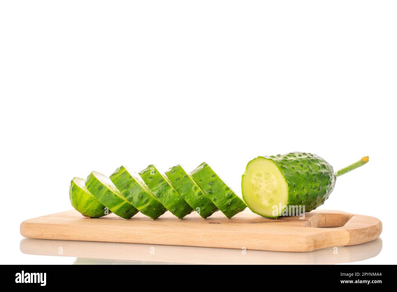One ripe cucumber gherkin cut into slices on a wooden kitchen board ...