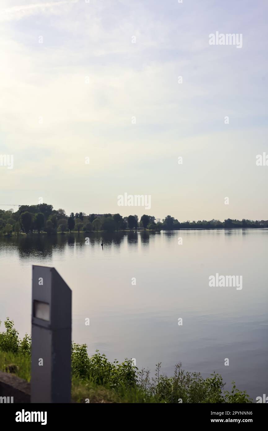 Lake and town by the shore casted in the water at sunset seen from afar ...