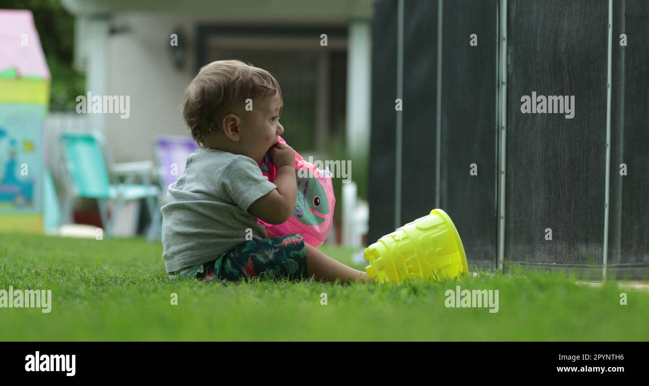 Baby toddler putting object in mouth outdoors in backyard Stock Photo ...