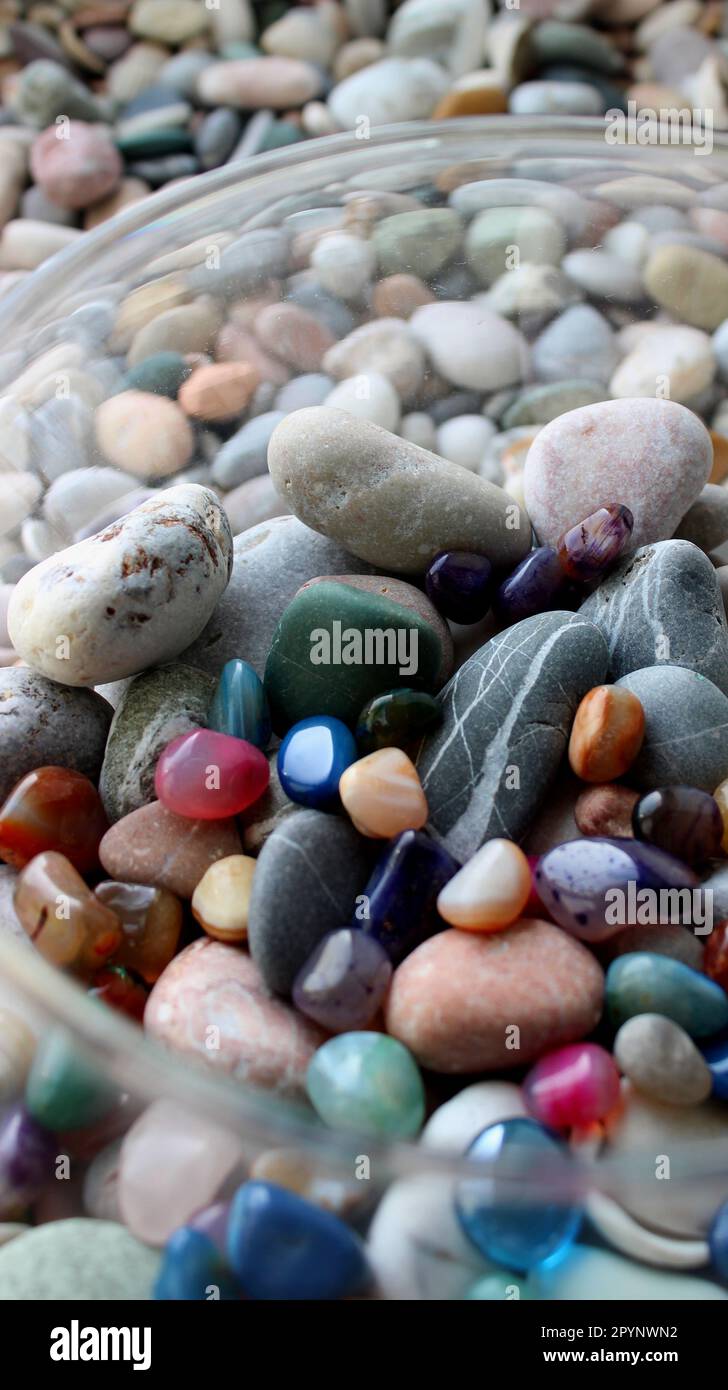 Edges of a decorative glass pot with multicolored quartz stones over a ...