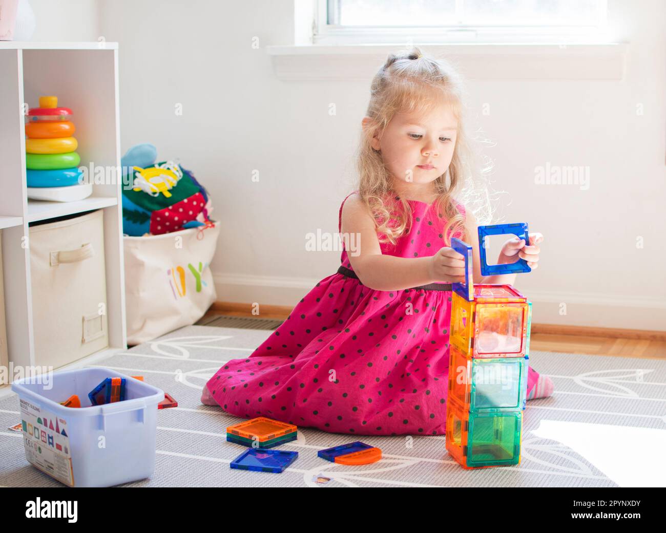 Little child playing with magnet tiles. Toddler caucasian girl playing ...