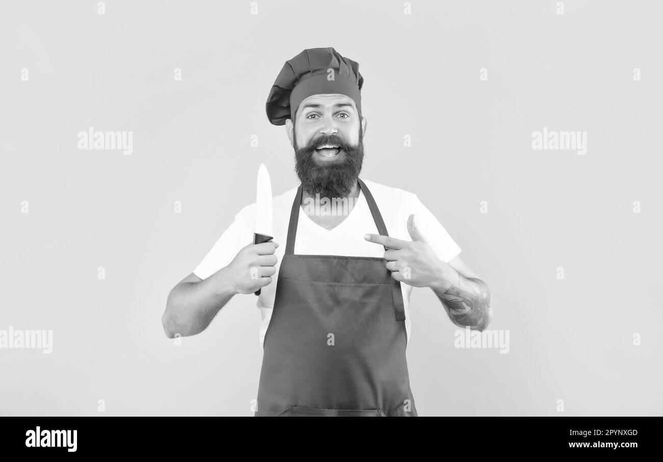 Happy man in red apron and toque pointing finger at cooks knife yellow ...