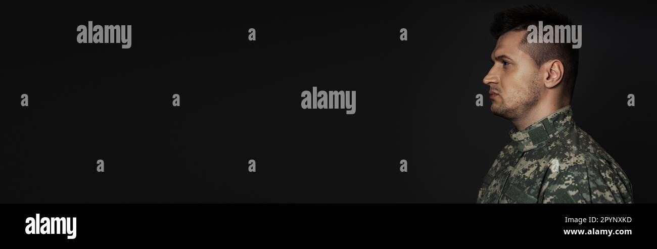 side view of sad soldier in military uniform isolated on black, banner ...