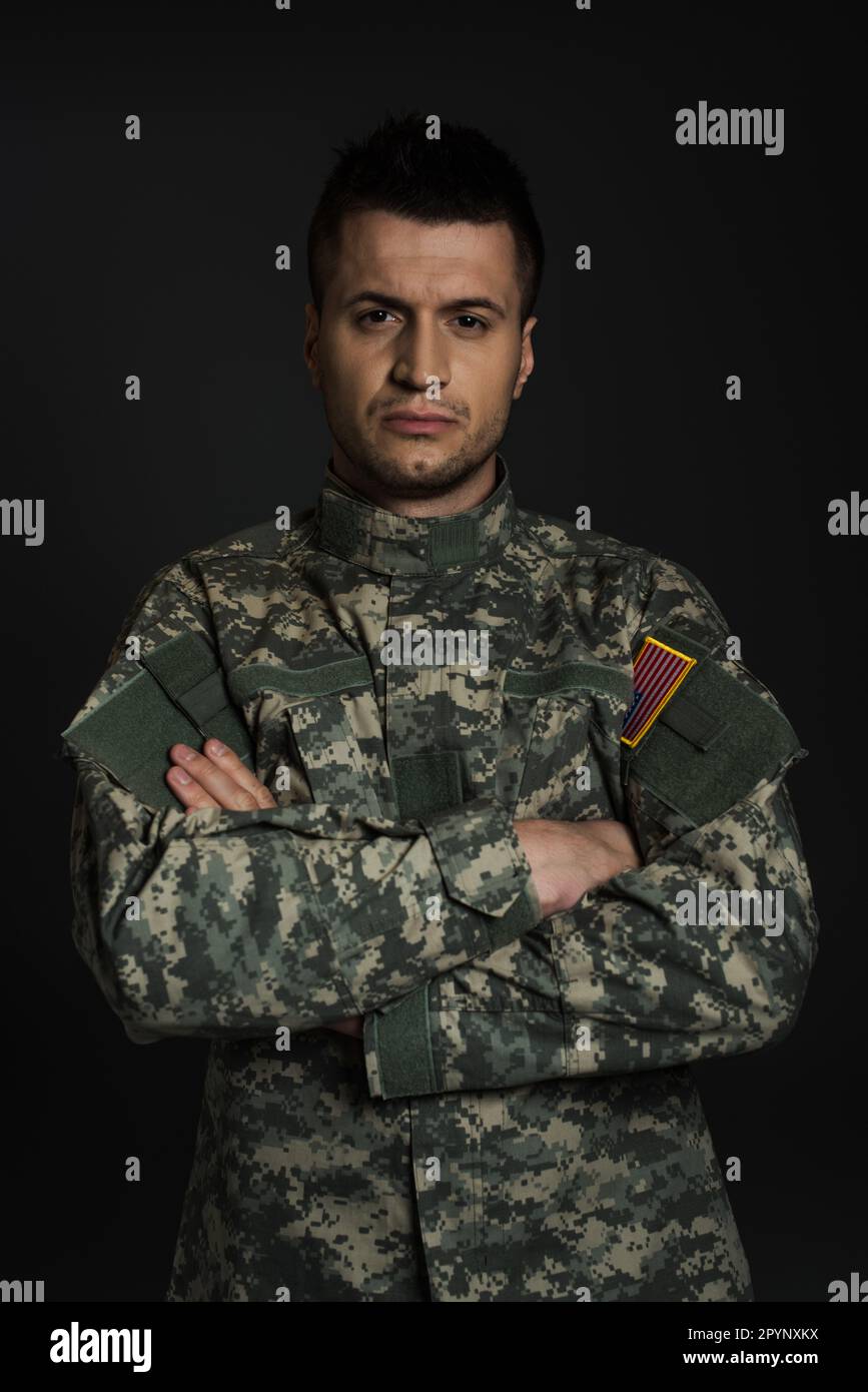 depressed American soldier in uniform standing with crossed arms isolated on black,stock image ...