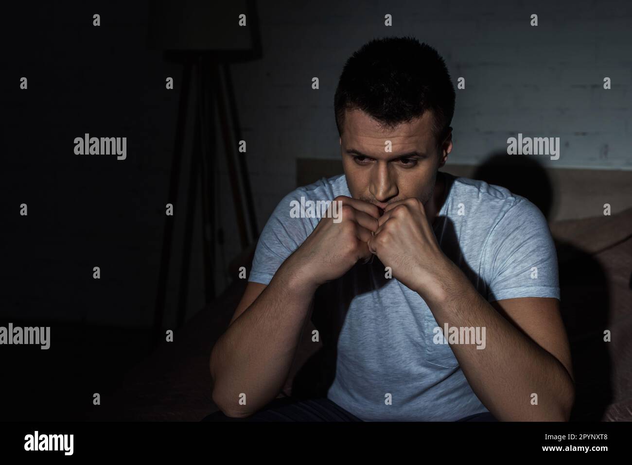 depressed man in white t-shirt sitting on bed while struggling from ...