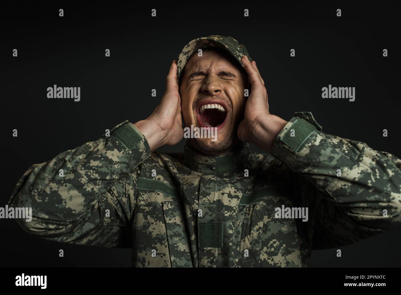 stressed soldier in camouflage uniform and cap screaming while ...