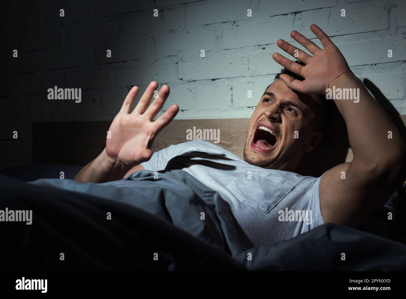 scared young man with ptsd having nightmares and screaming at night ...