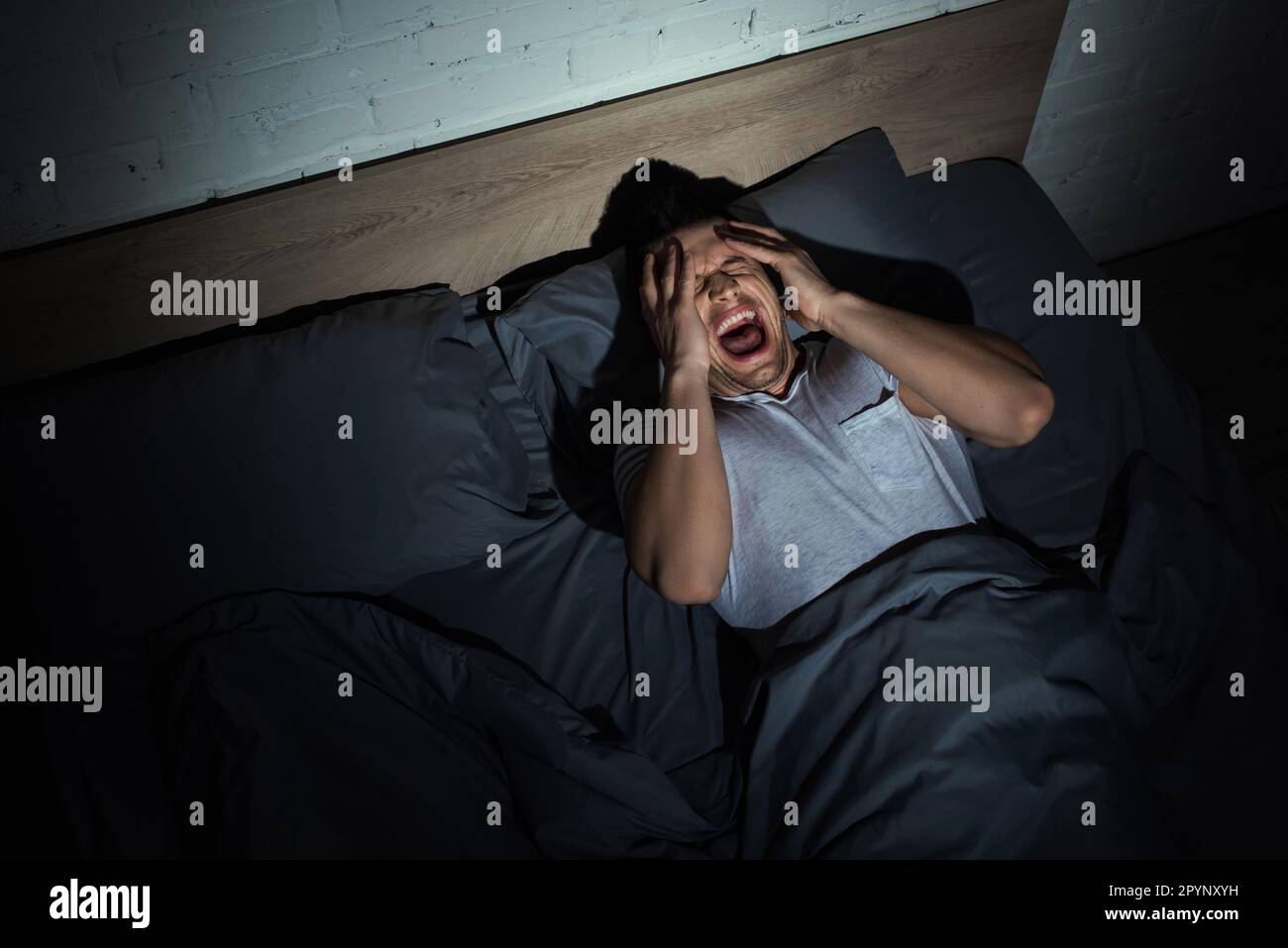 top view of young man screaming while having nightmares and panic ...