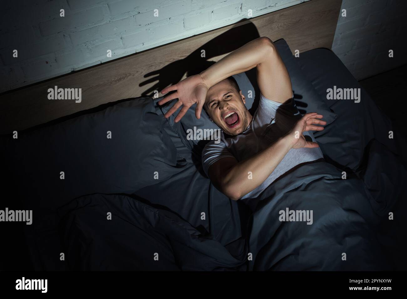 top view of stressed man screaming while having nightmares and panic ...