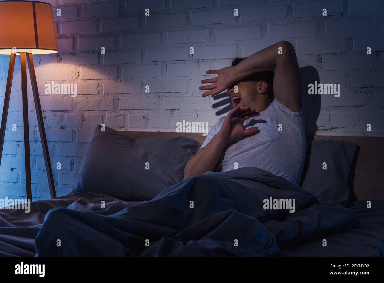 scared young man with ptsd having flashbacks while screaming at night ...