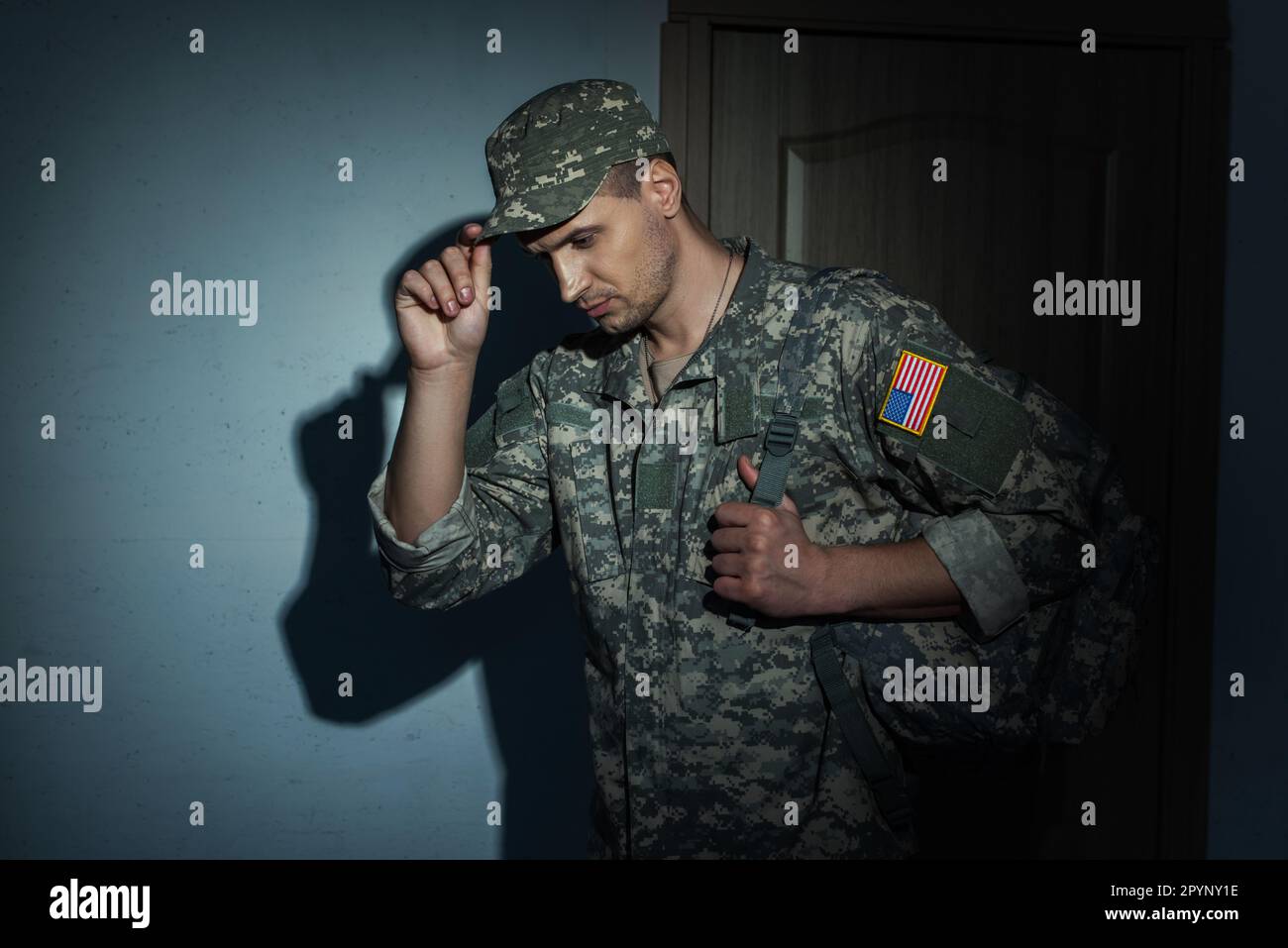 American military man taking off cap while coming back home at night ...