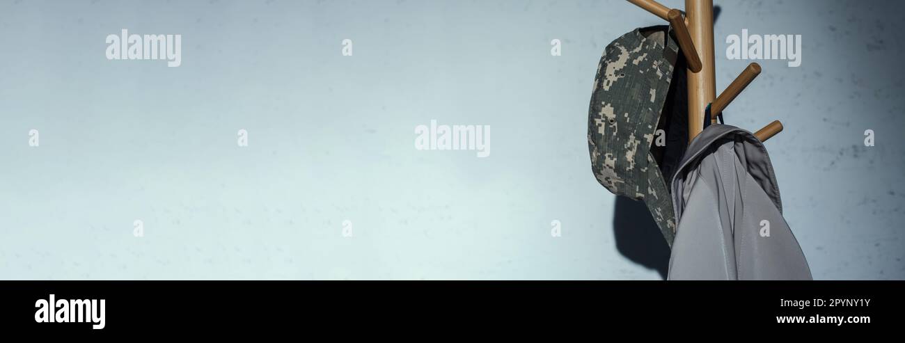 Military cap with camouflage pattern hanging on floor hanger at home ...