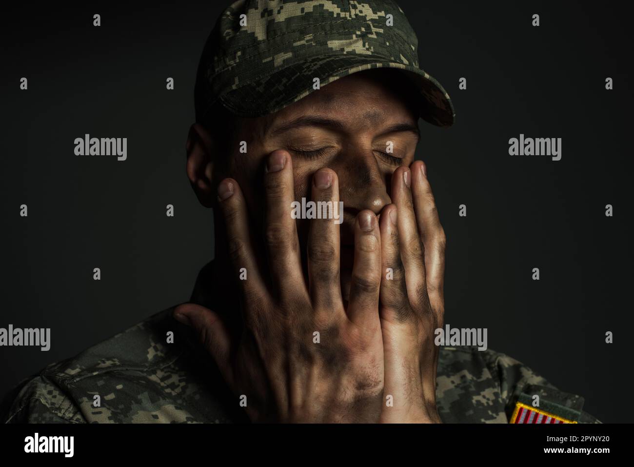 military man with closed eyes covering face with dirty hands and ...