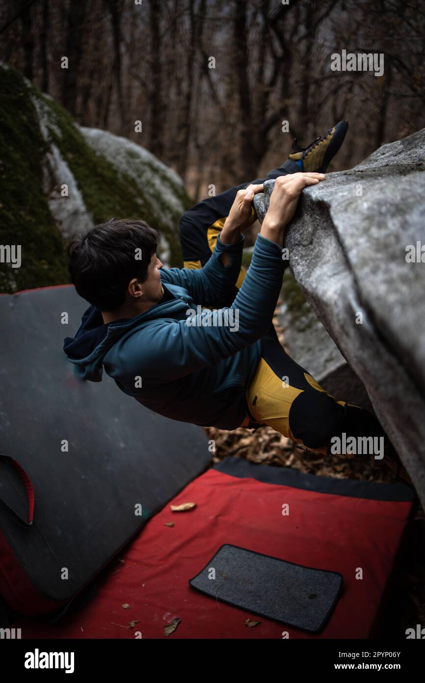 A rock climber climbing on a boulder rock outdoors. Group of friends ...