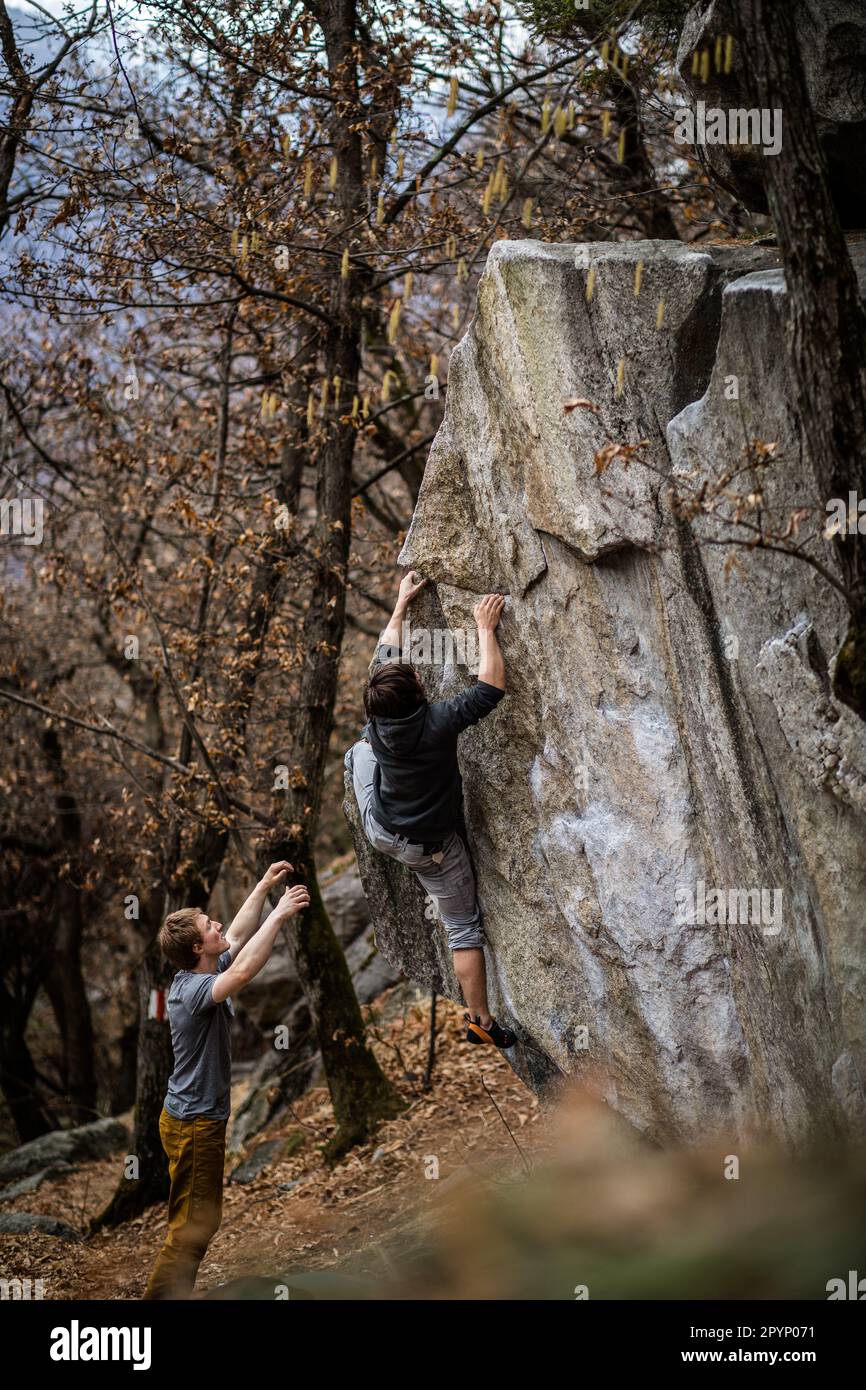 A rock climber climbing on a boulder rock outdoors. Group of friends ...