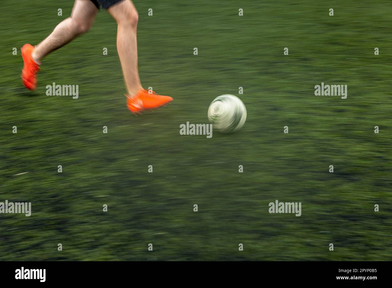 Fast moving feet of a soccer player on a pitch during a match (panned ...
