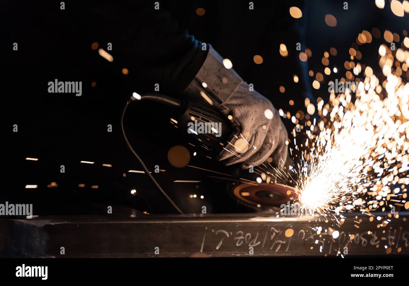 Man working on iron with grinder. Man at work. Sparkles and fire from ...