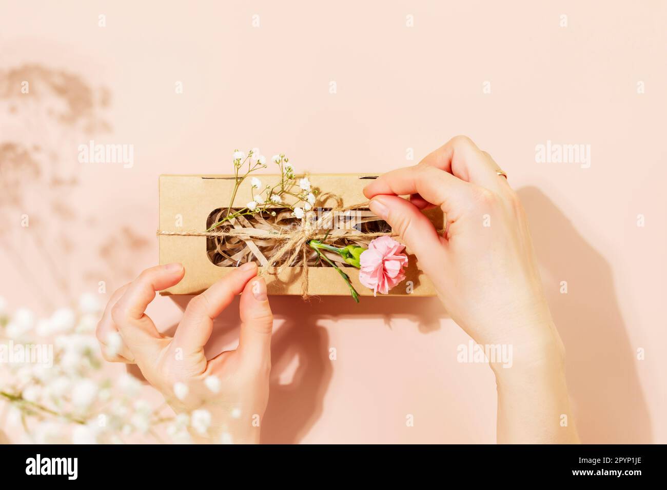 Women's hands untie the ribbon on gift box with tender flowers Stock ...
