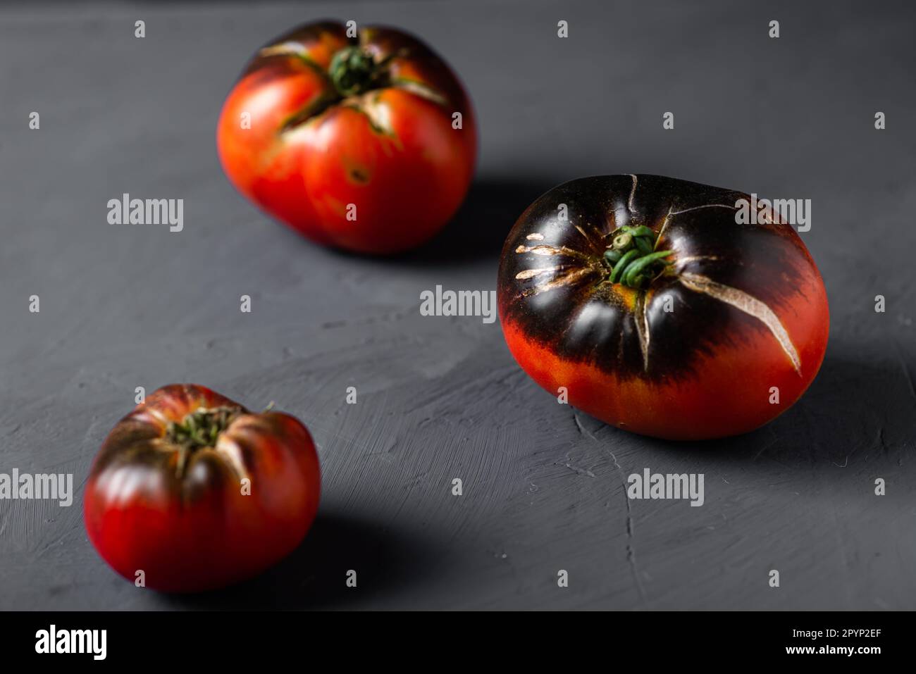 Red-black tomatoes of the bovine heart variety on a black background ...