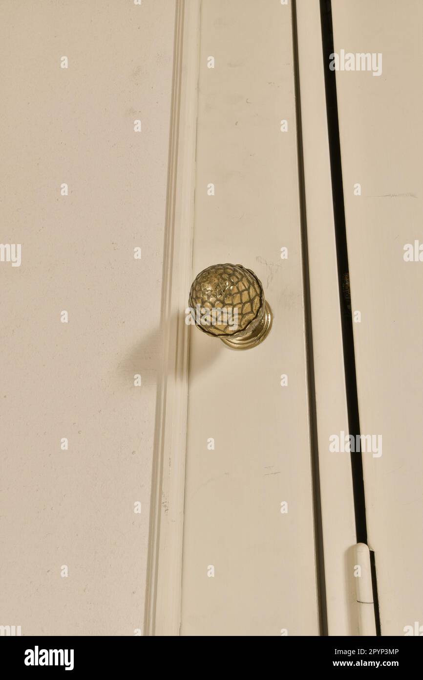 a door handle on the side of a white cabinet with peeling paint and ...