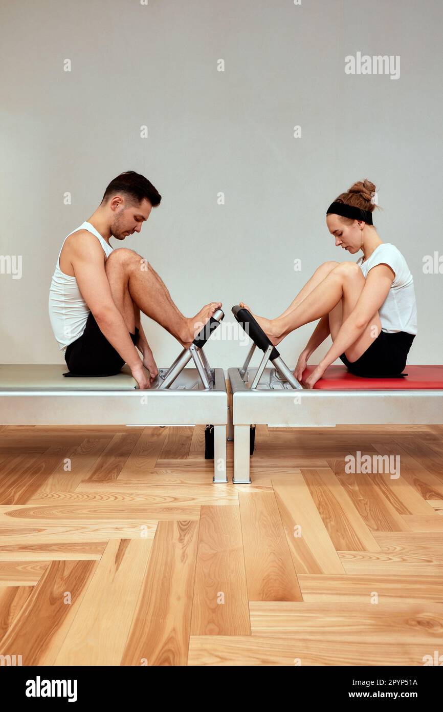 Couple doing pilates on a reformer, group pilates training in a studio ...