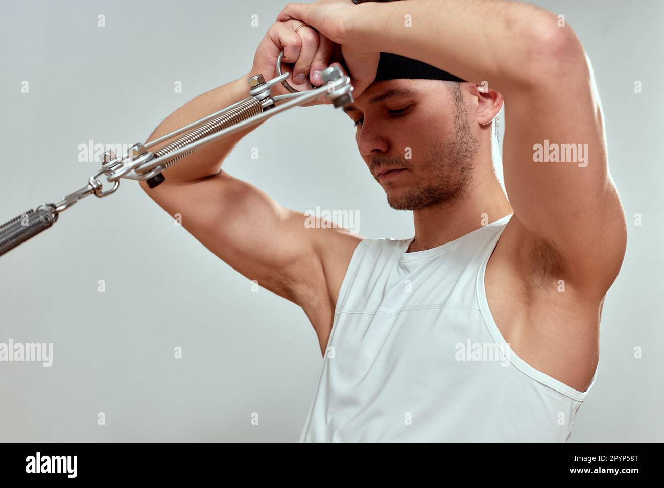 A young man is engaged on a simulator in a Pilates studio, training ...