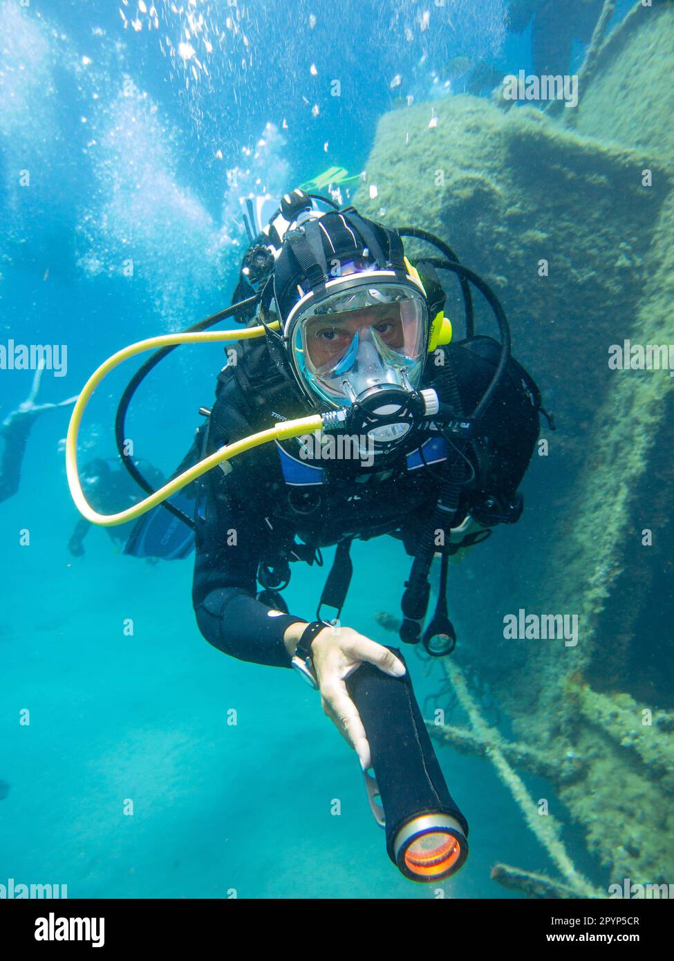 Scuba Divers exploring a shipwreck on the sandy bottom of the sea with ...