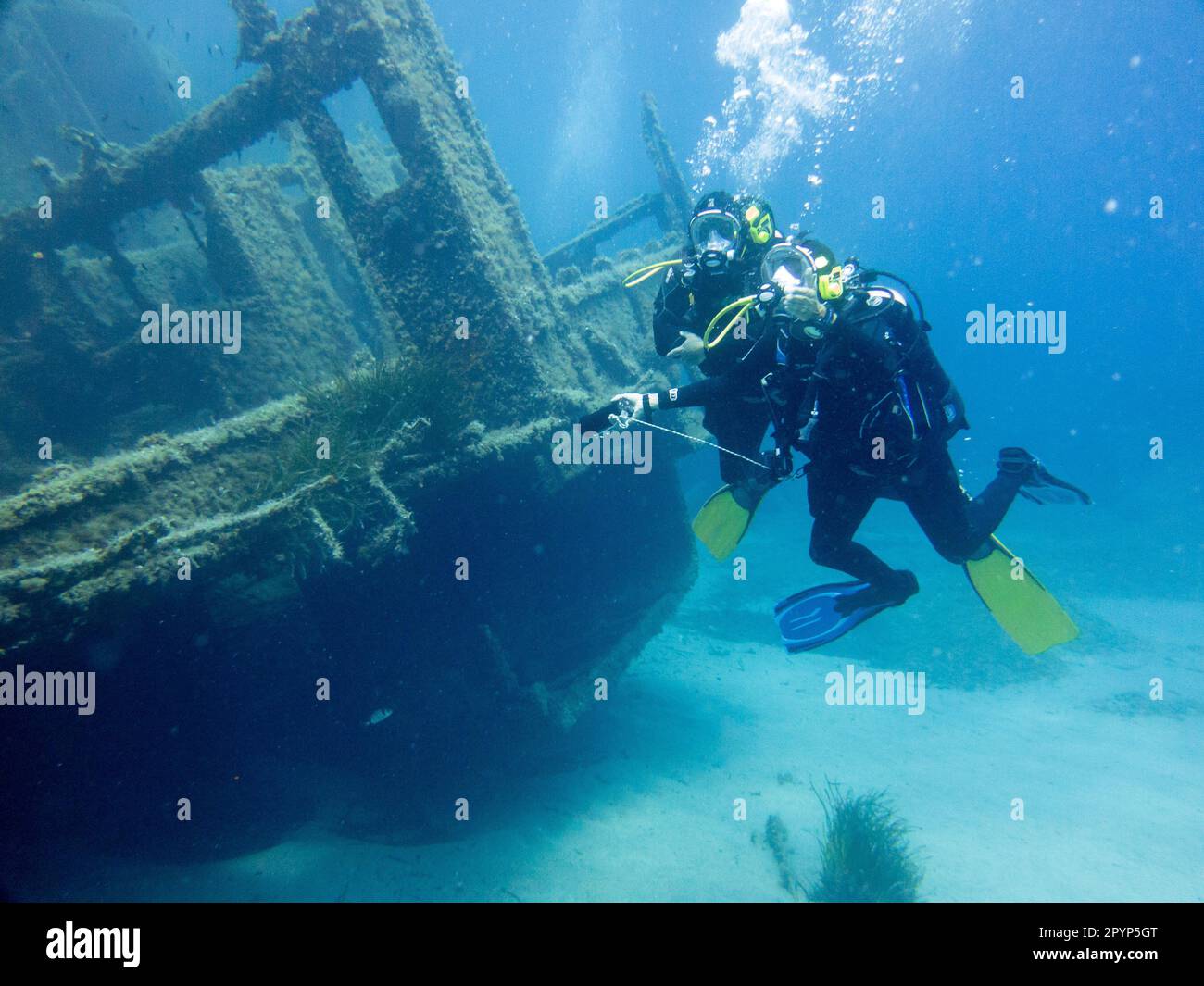 Divers exploring a shipwreck on the sandy bottom of the sea Stock Photo ...
