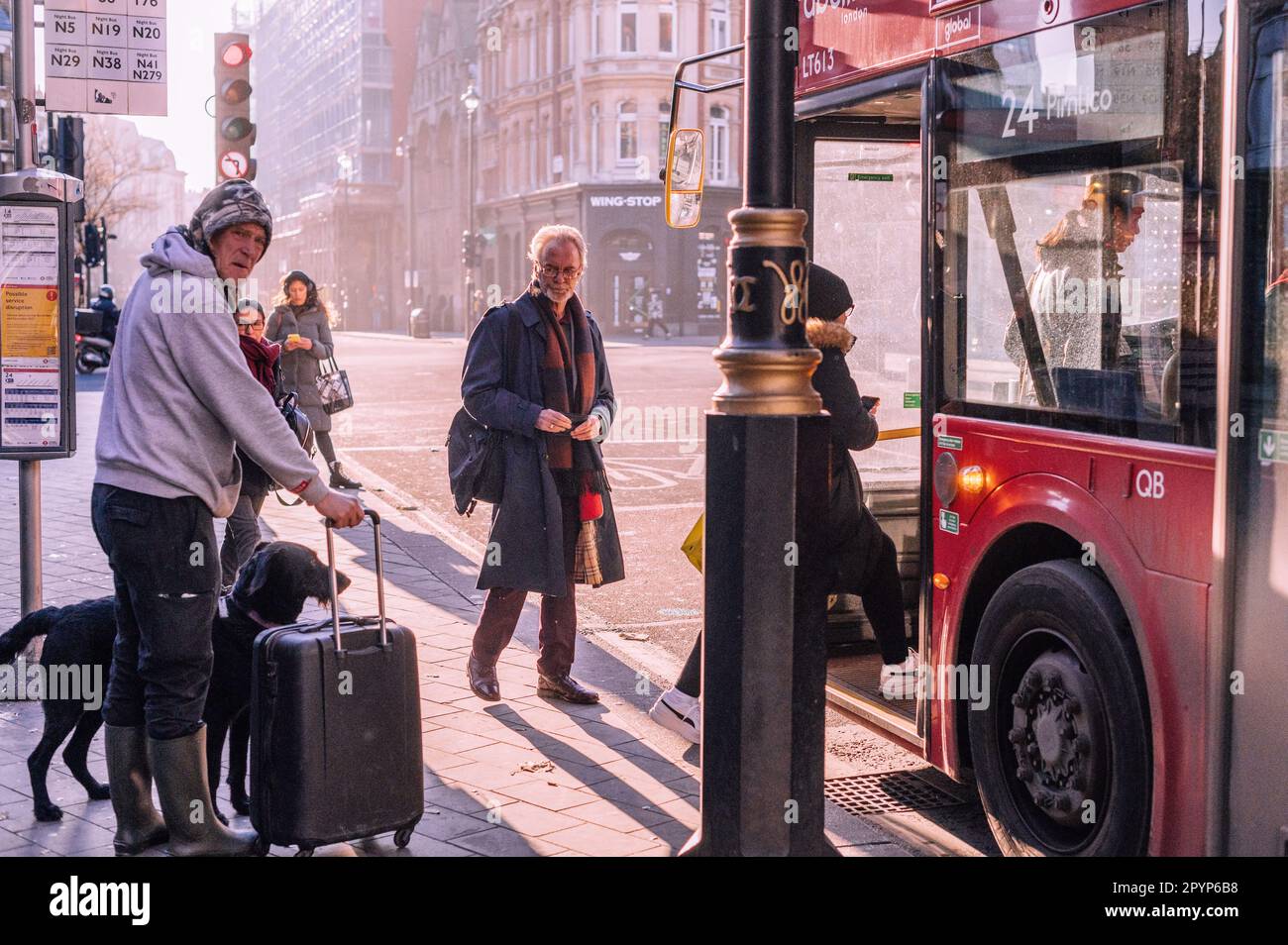 A group of travelers carrying suitcases getting onto a city bus at a ...