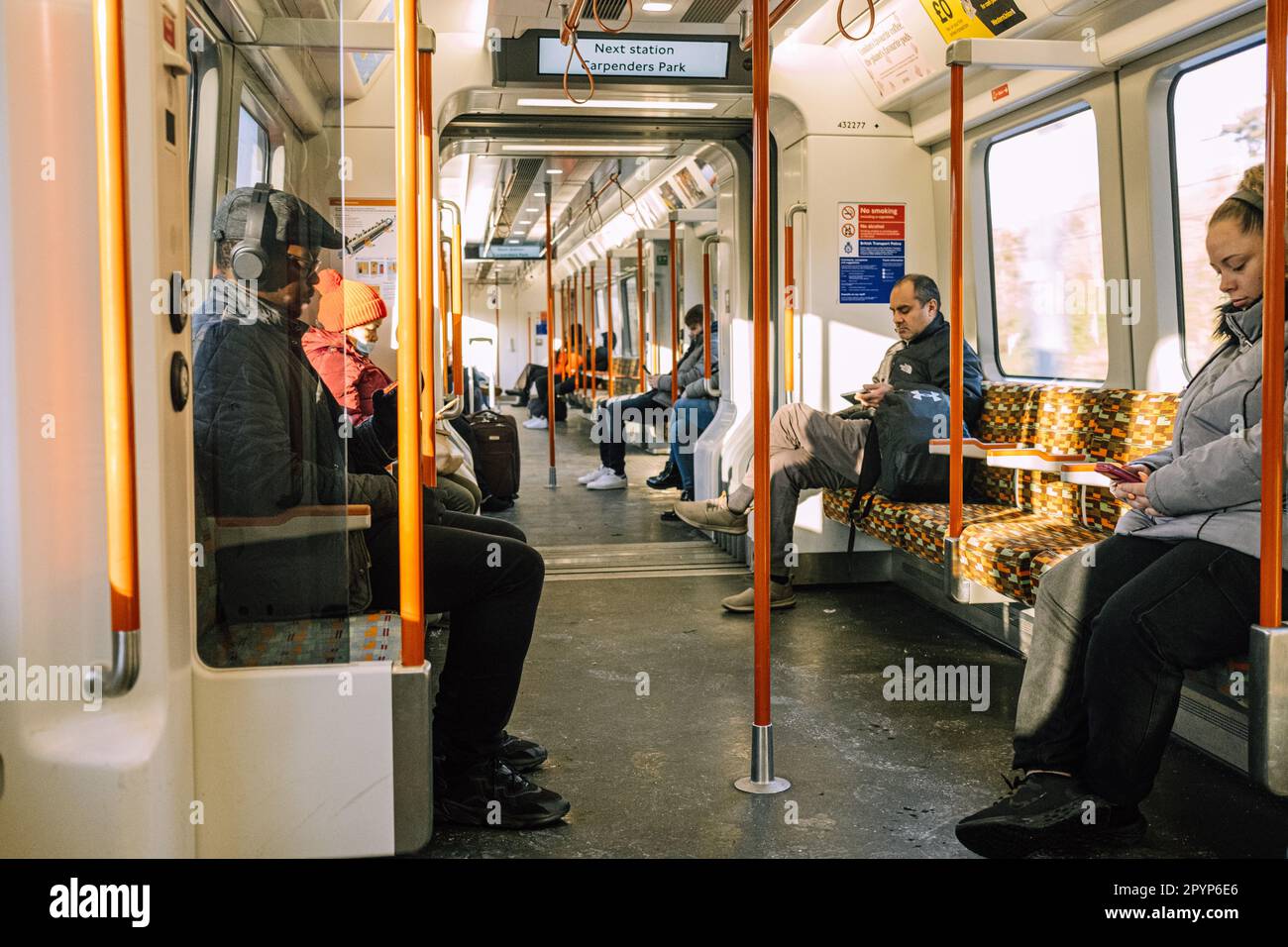 An interior view of a subway train with several passengers seated and ...