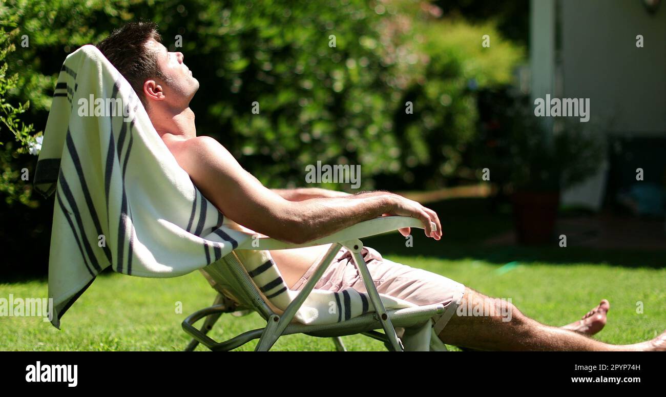 Man sunbathing outside in home lawn. Person outdoors relaxing Stock ...