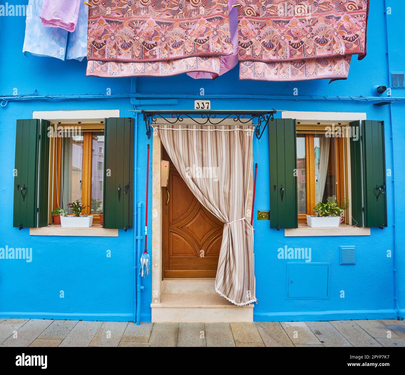 A charming European house, with two Windows, hanging flowers and red ...