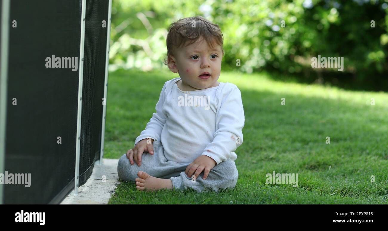 Cute baby on grass backyard. Infant observing surroundings Stock Photo ...