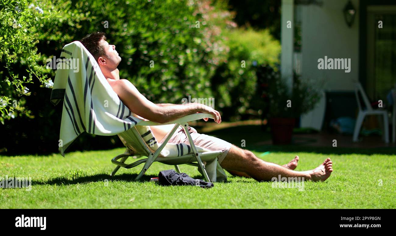 Handsome man outside in backyard sunbathing. Person relaxing during ...