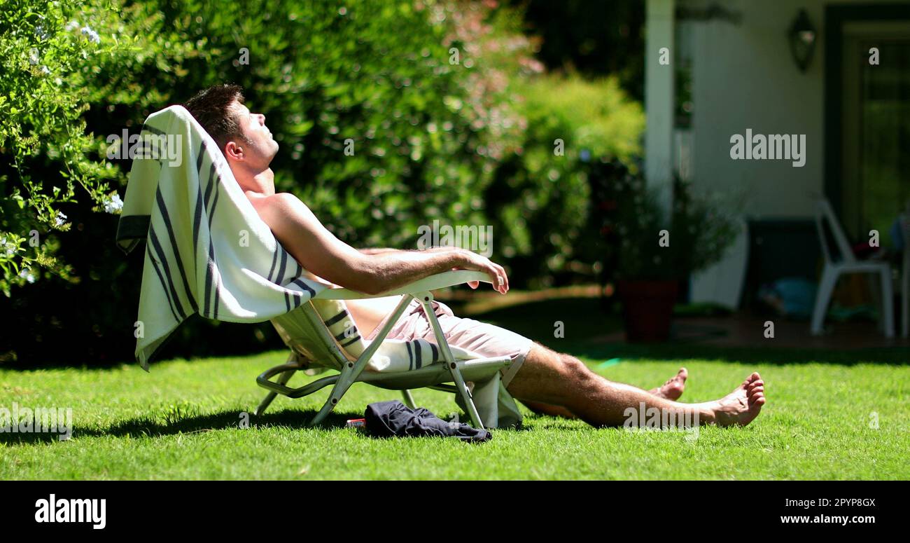 Handsome man outside in backyard sunbathing. Person relaxing during ...