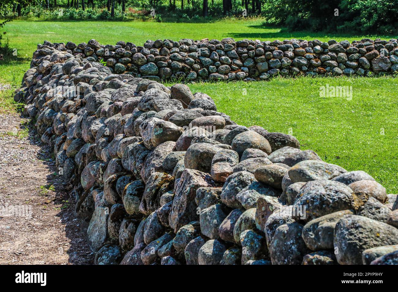 Corner of old dry stone wall amid grass meadow Stock Photo - Alamy