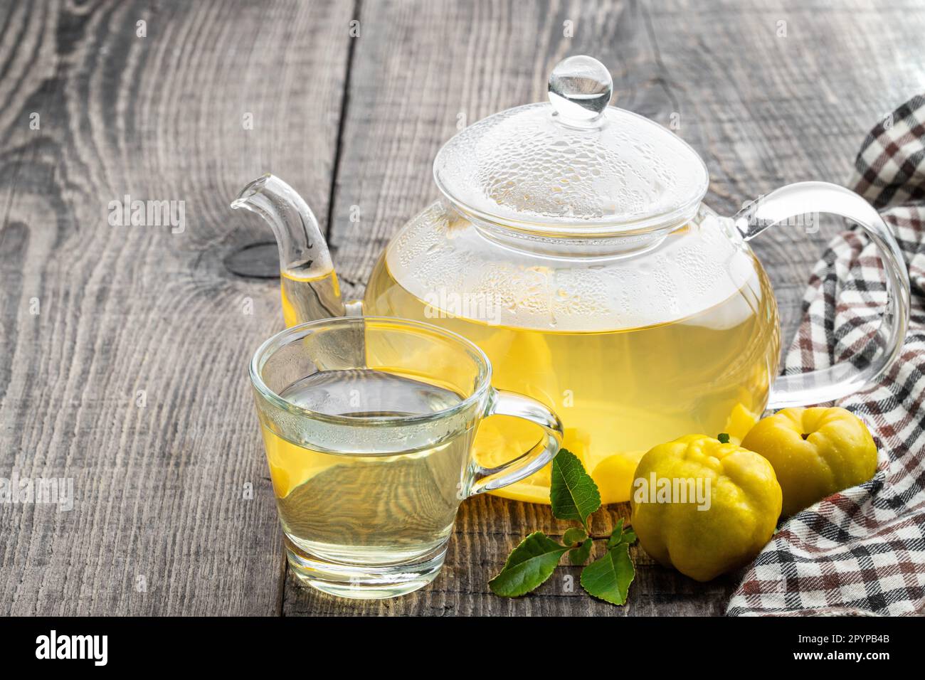 Hot quince tea in transparent teapot with fresh fruits on wooden table ...
