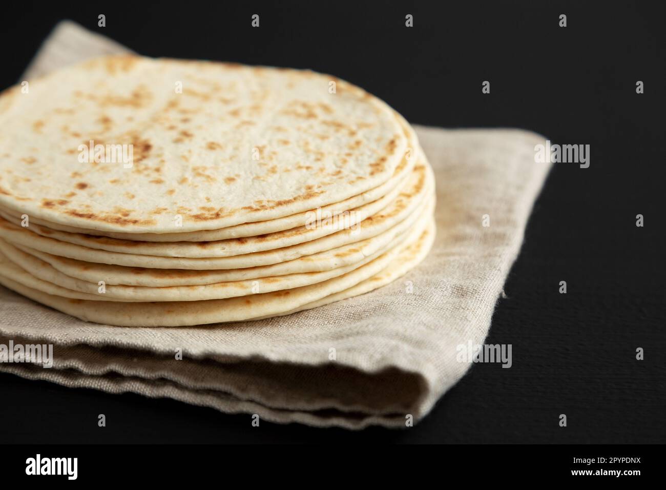 Stack of Whole Wheat Flour Tortillas on a black background, side view ...