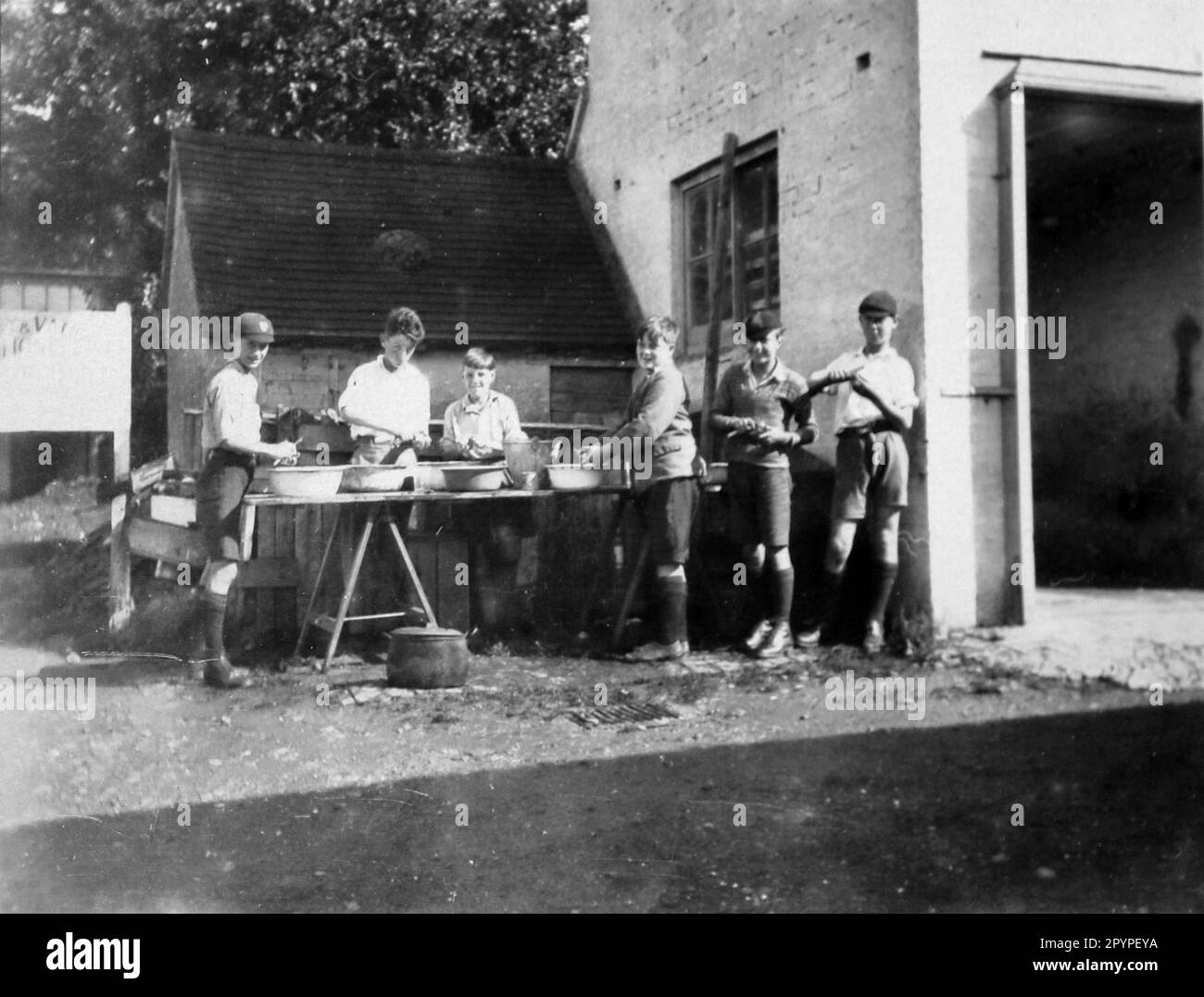 A group of boys preparing “spuds” on a long trestle table, c1930. From ...
