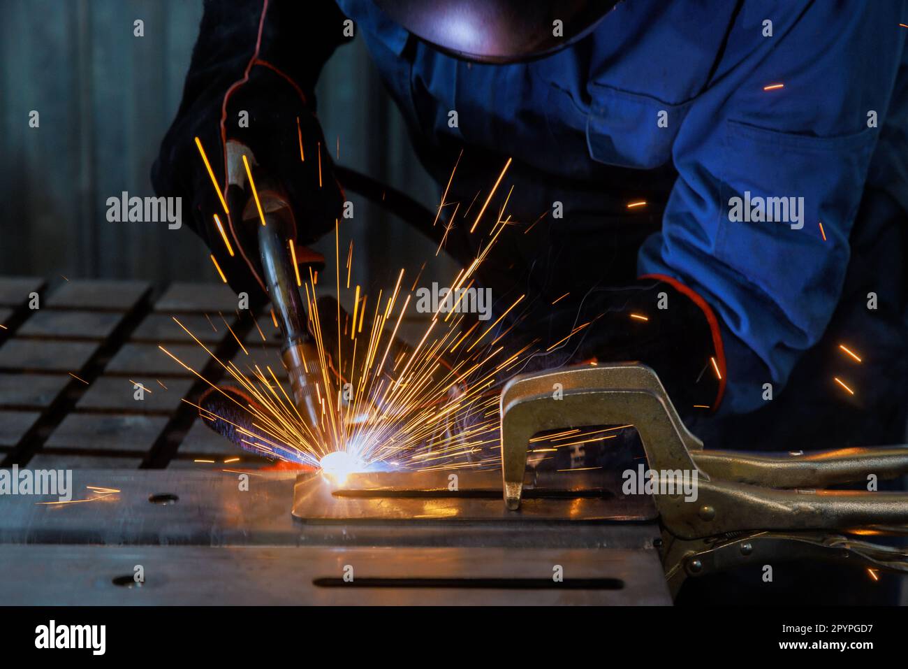 Workplace with worker welding steel at spark lighting smoke in factory ...