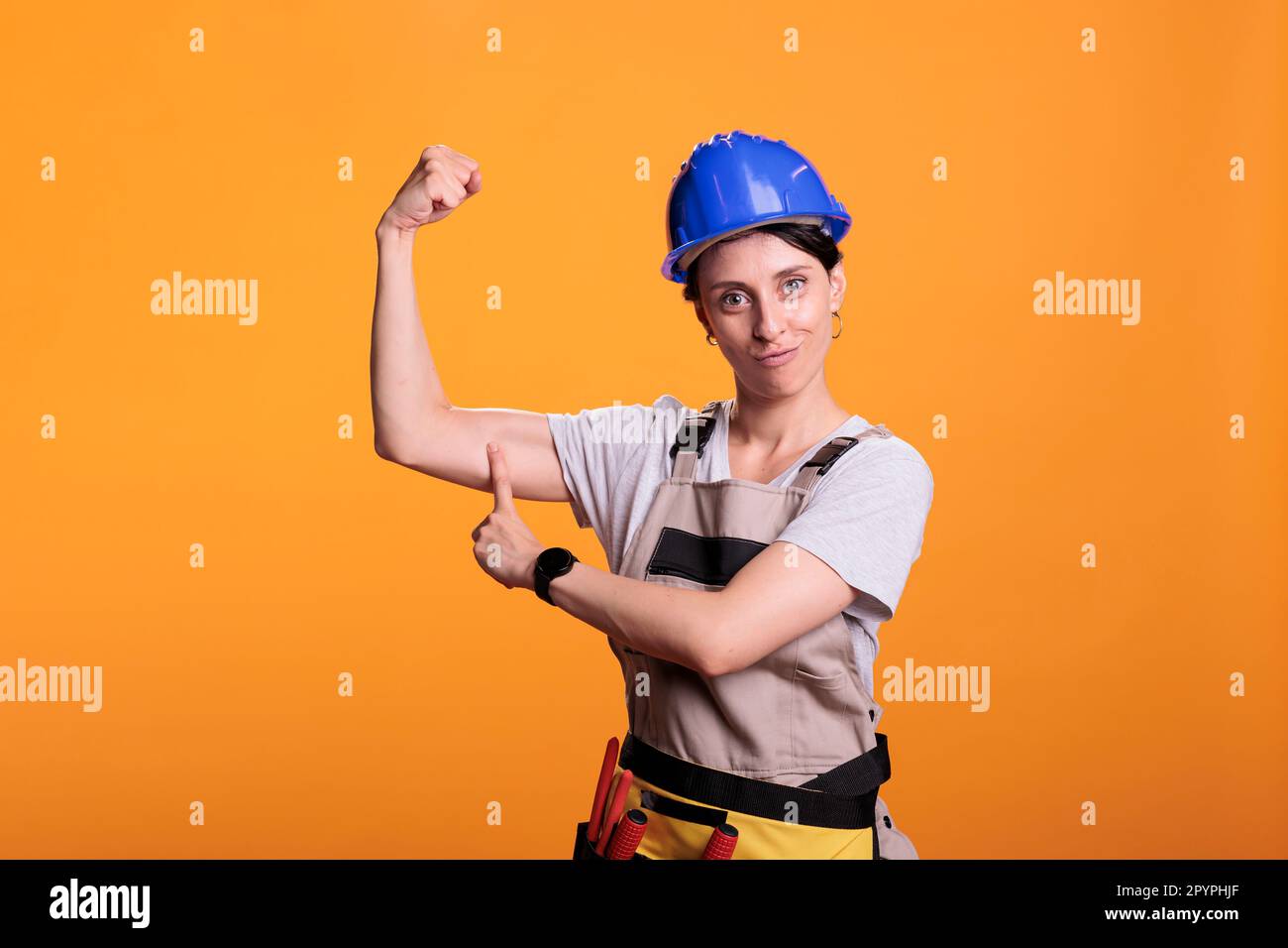 Strong woman builder flexing arm muscles, preparing to work on ...