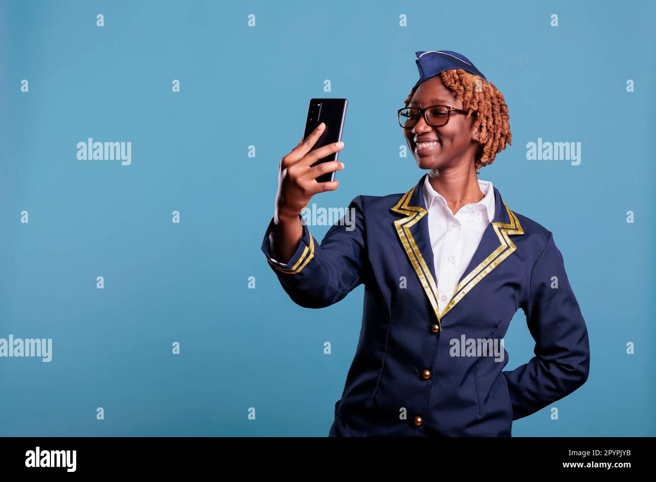 Smiling female flight attendant wearing uniform having video call with ...