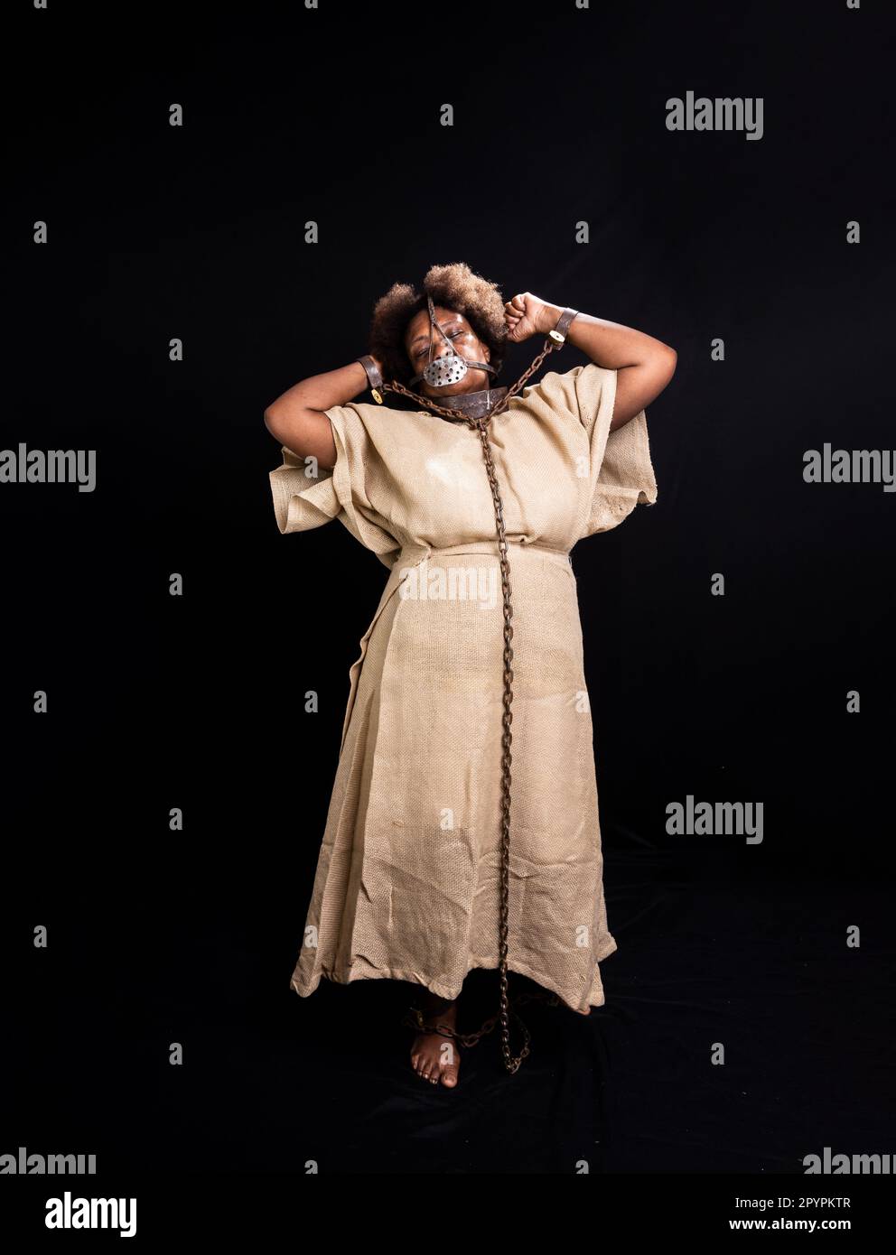 Portrait of a black woman in chains with an iron mask on her face ...