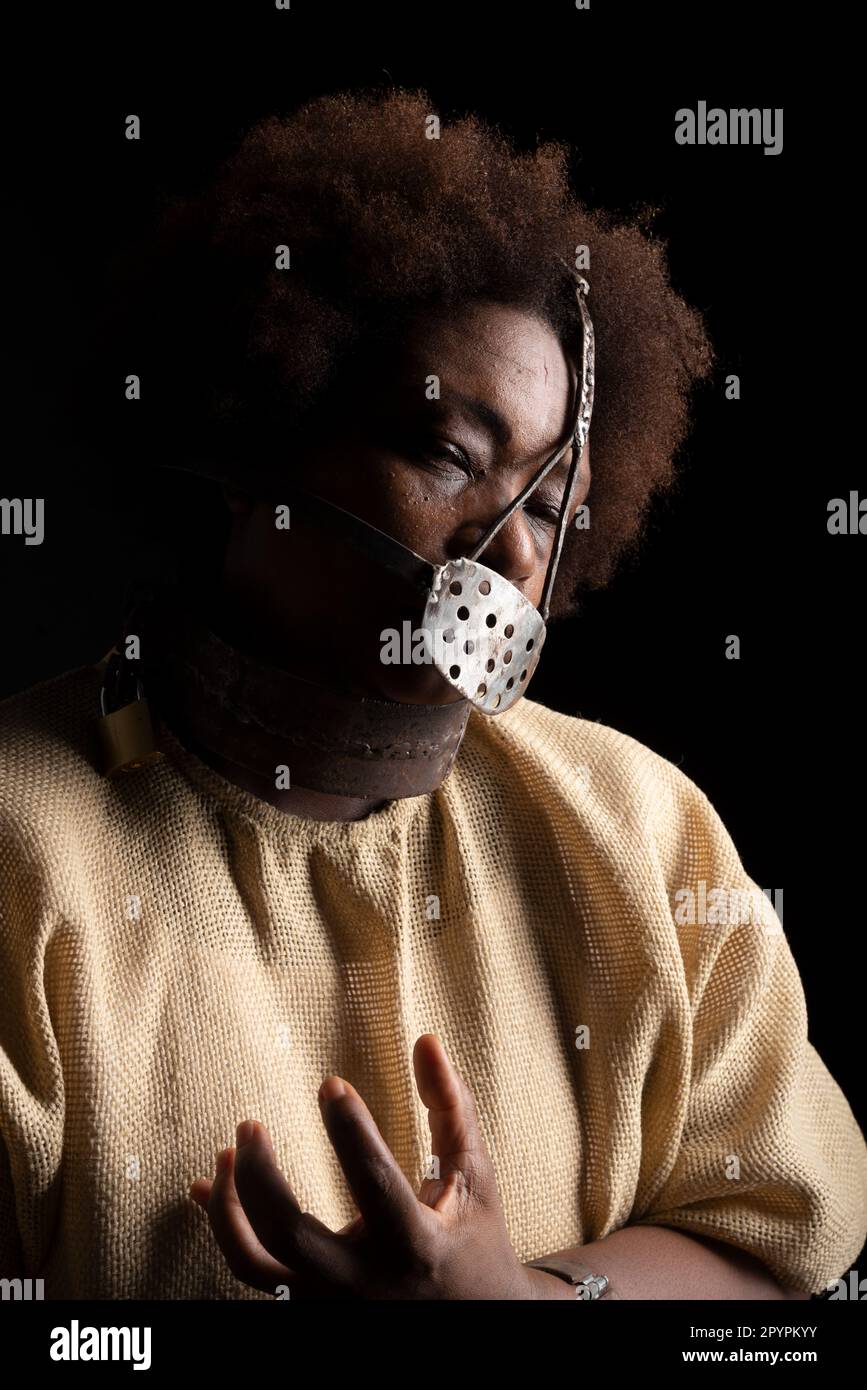 Portrait of a black woman wearing an iron mask on her face to represent ...