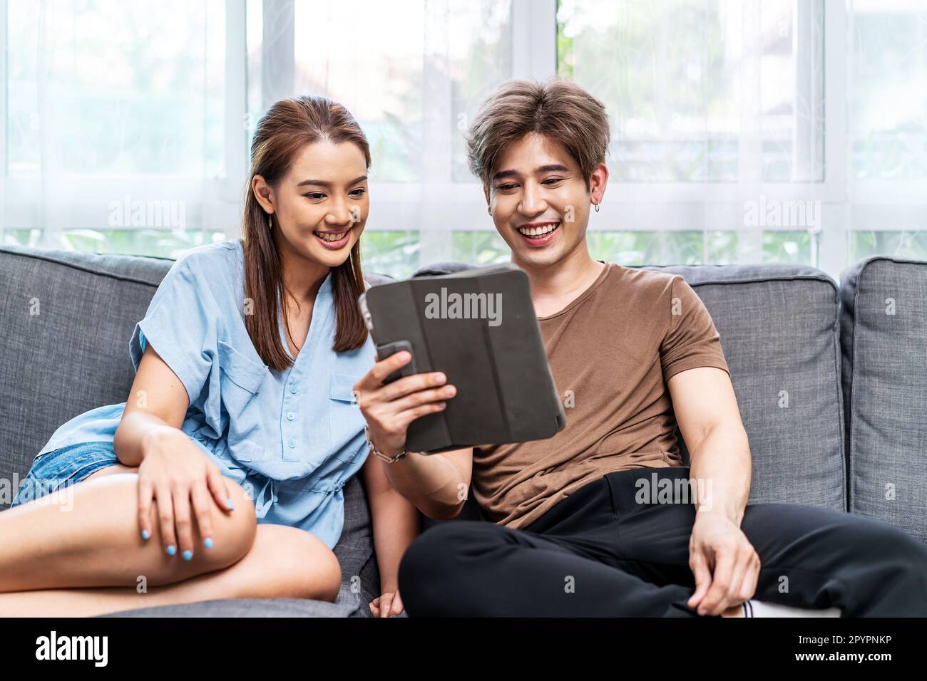 Portrait of an happy couple in love using a tablet, looking at digital ...
