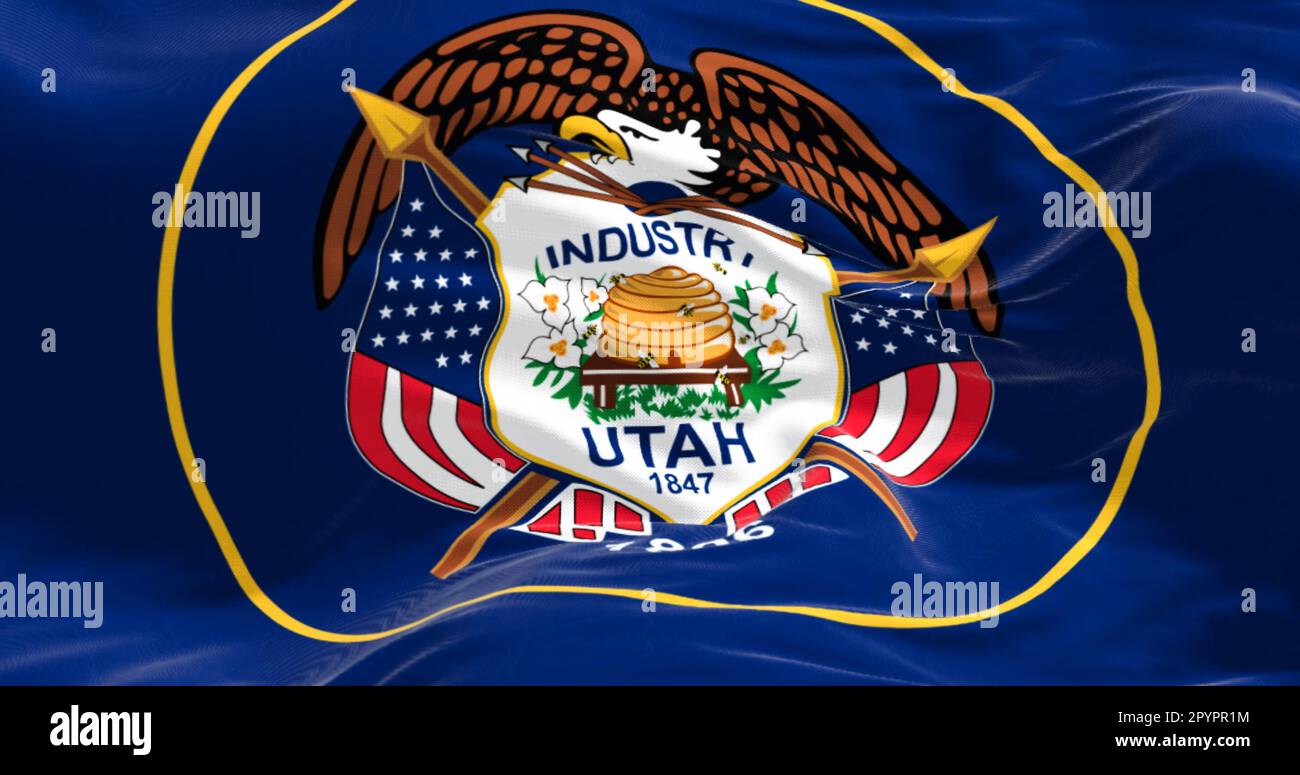 The Utah state flag fluttering in the wind. State seal surrounded by a ...