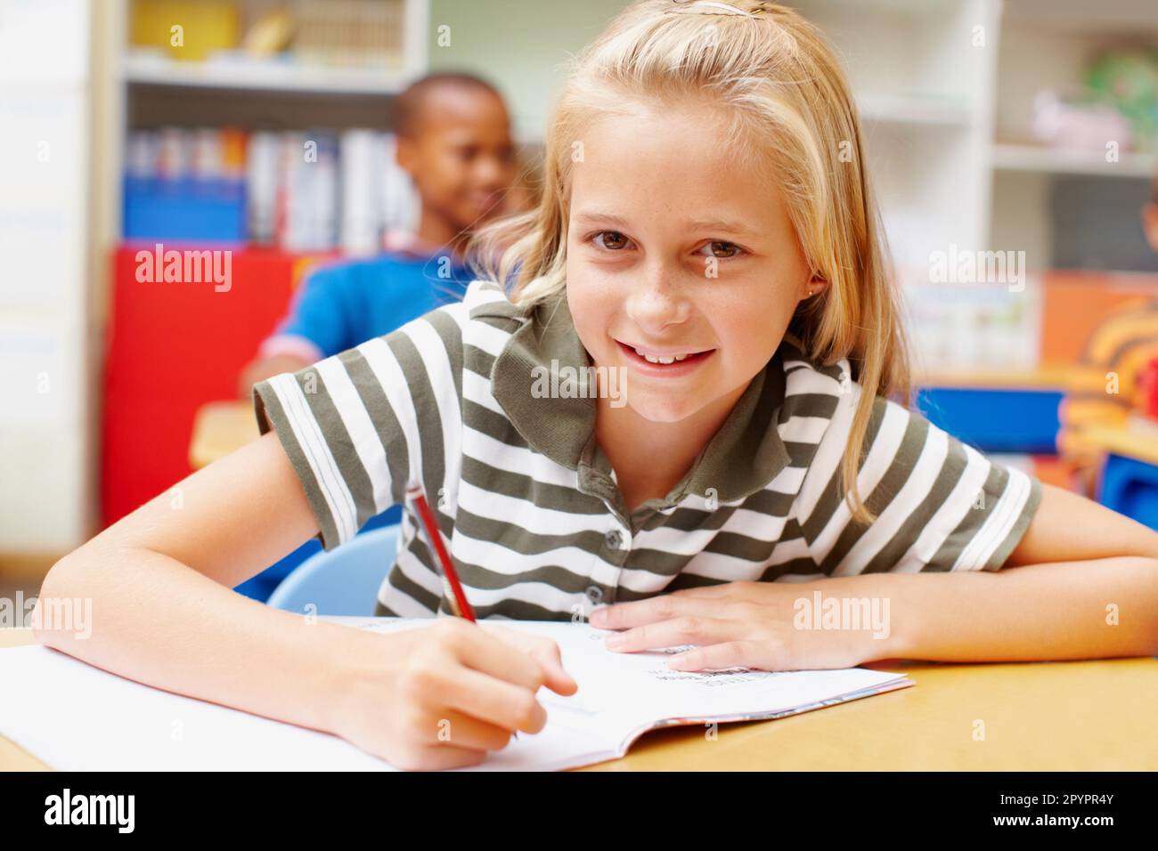 Feeling fresh and ready to learn. Sweet primary school girl writing in ...