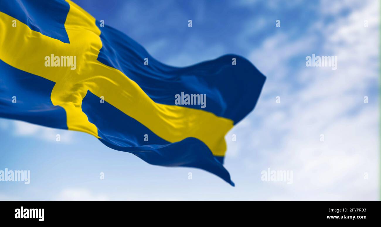 National flag of Sweden waving on a clear day. Yellow Nordic cross on a ...