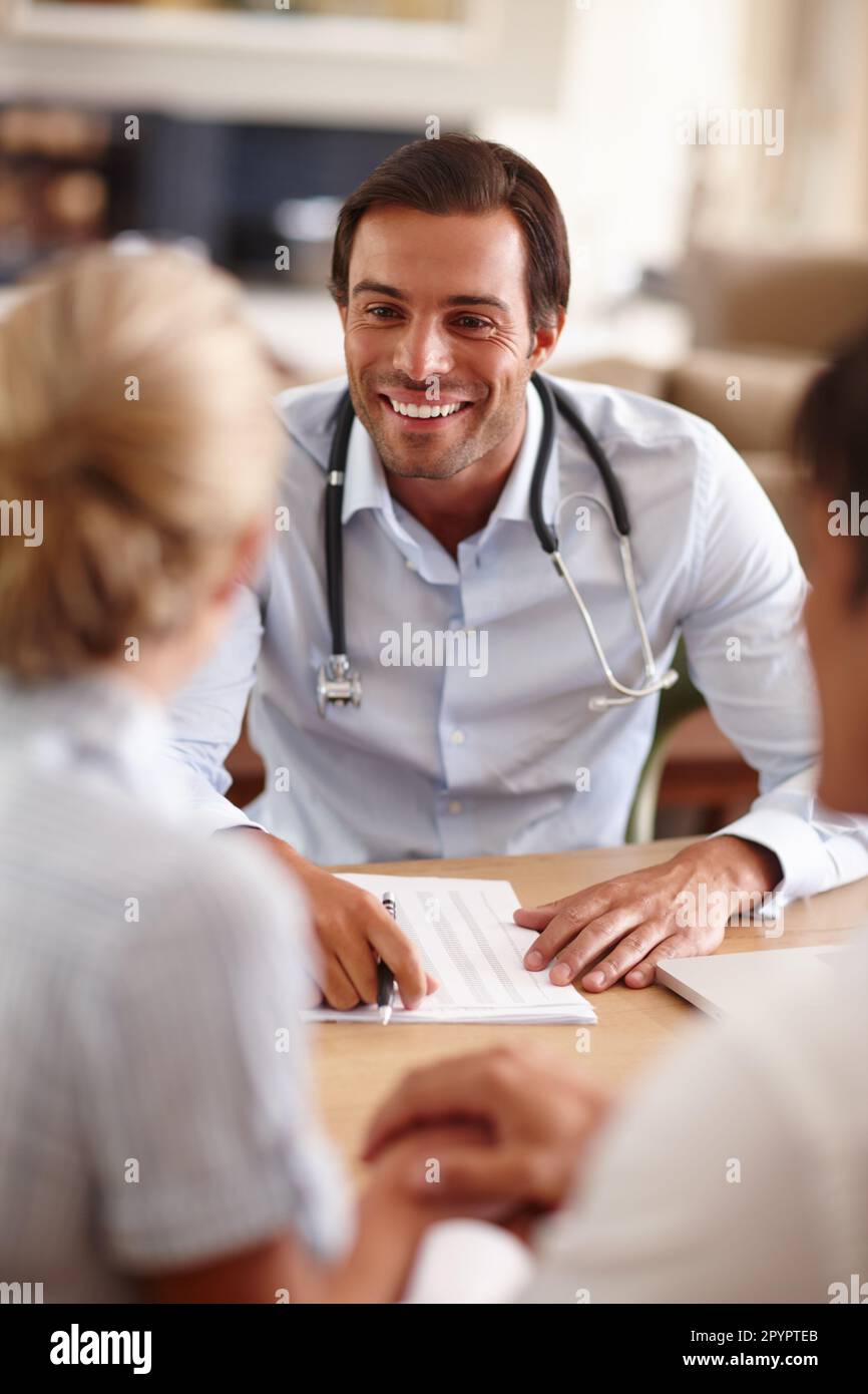 Giving them the good news. a male doctor giving good news to a couple ...