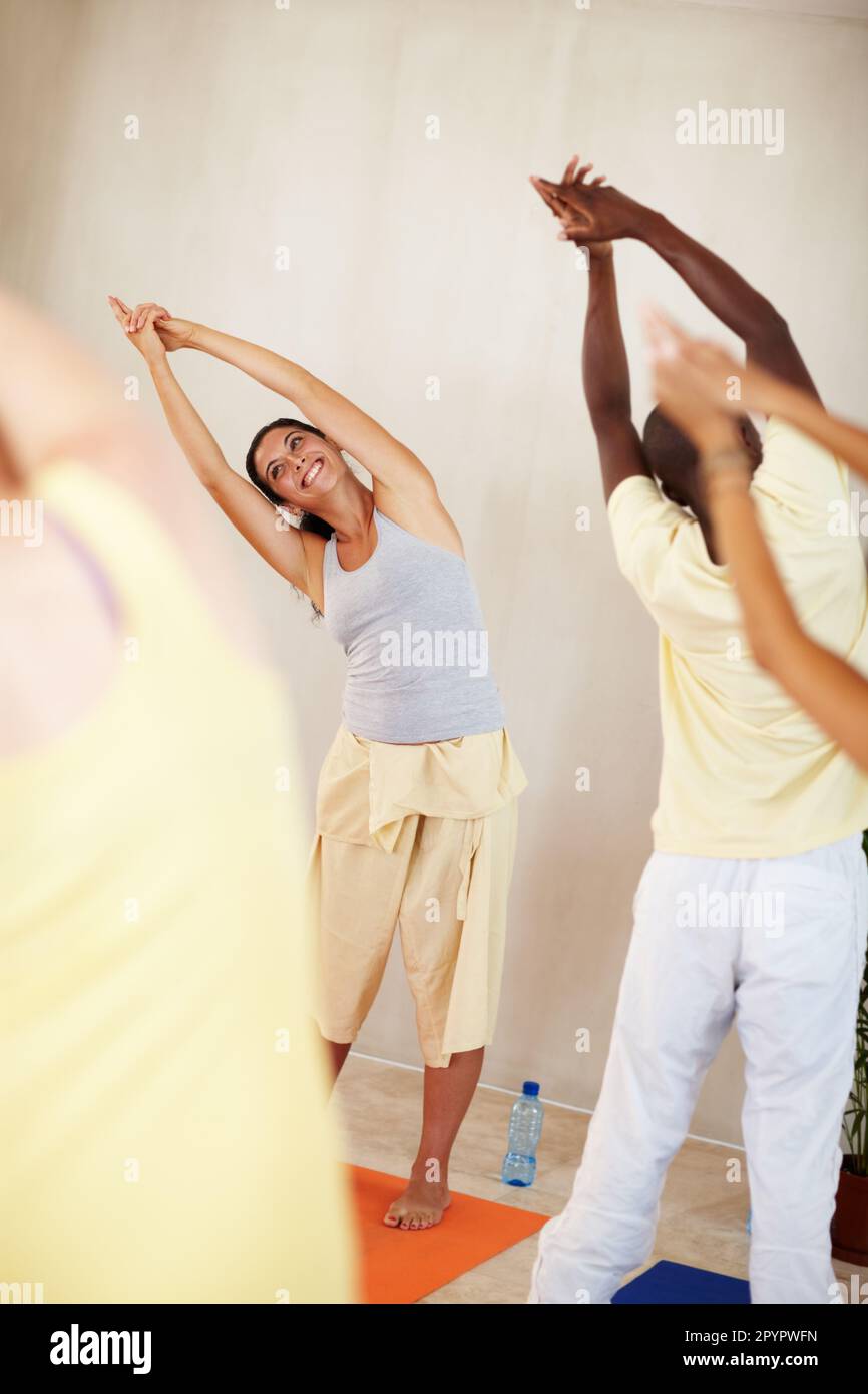 She loves instructing. A pretty yoga instructor leading her class in a ...